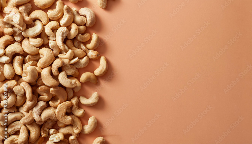 Top down view of cashew nuts scattered on a peach fuzz color background ...