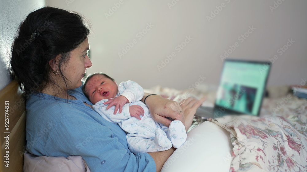 New mother bonding with her newborn baby while working on a laptop in a ...