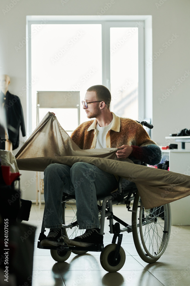 Young male fashion designer with disability holding rolled textile on ...