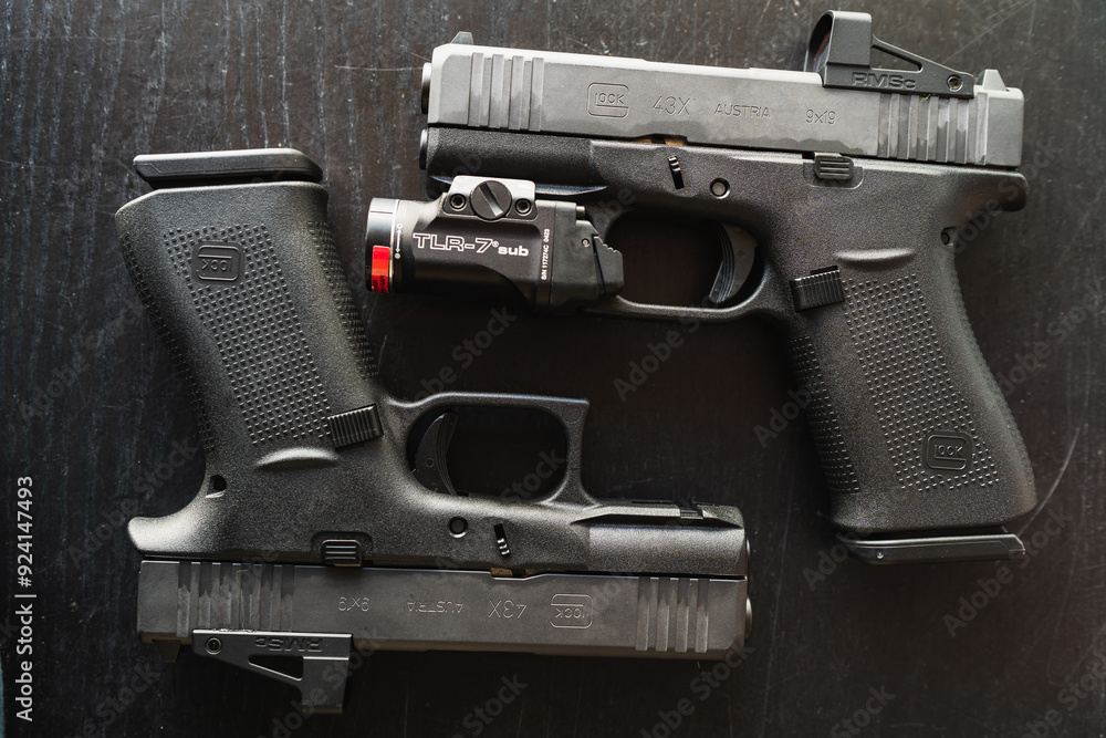 Baltics, August 12, 2024. Two modern glock 43x compact pistols with red ...