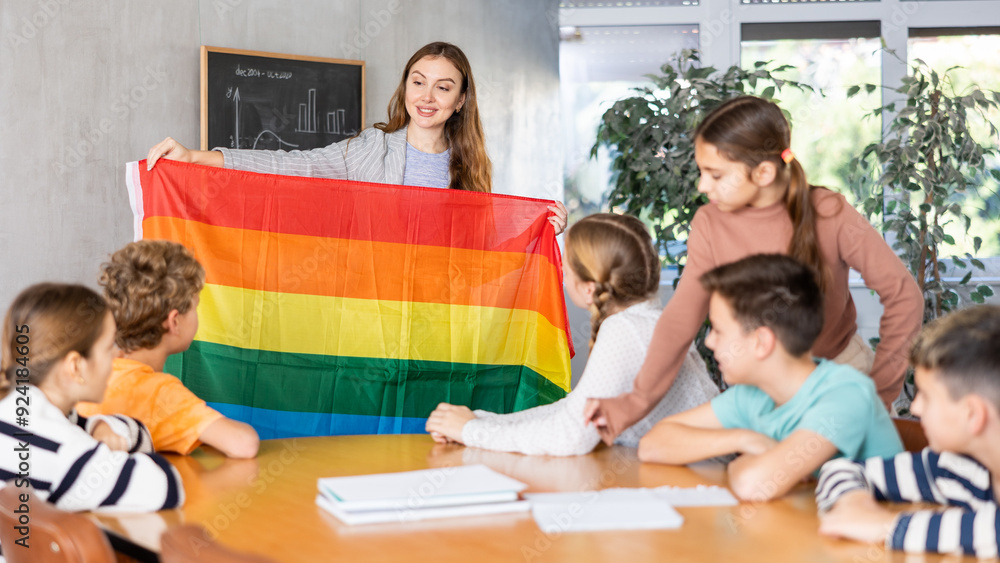 Young female teacher showing flag of LGBT to schoolchildren preteens ...