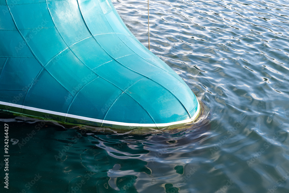 The bulbous bow of a blue boat with a cream color stripes. The ship has ...