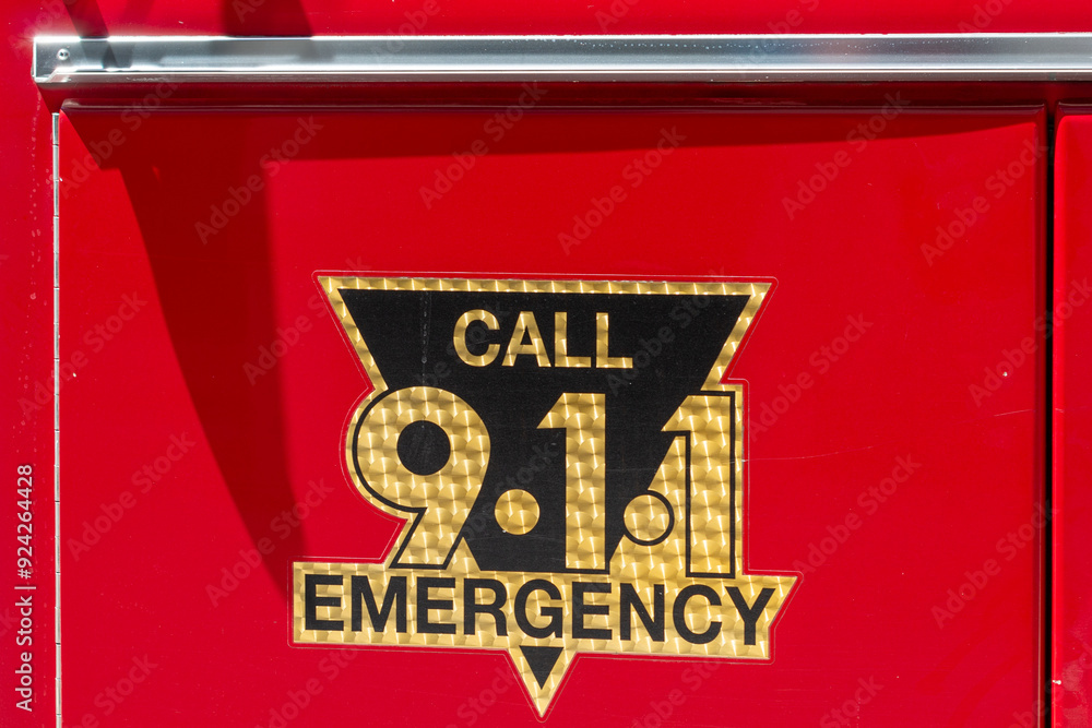 A black triangle with the message to call 911 in case of an emergency ...