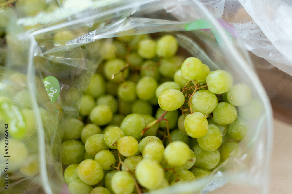 A bunch of sour green grapes on stems in a clear plastic bag. The fresh ...