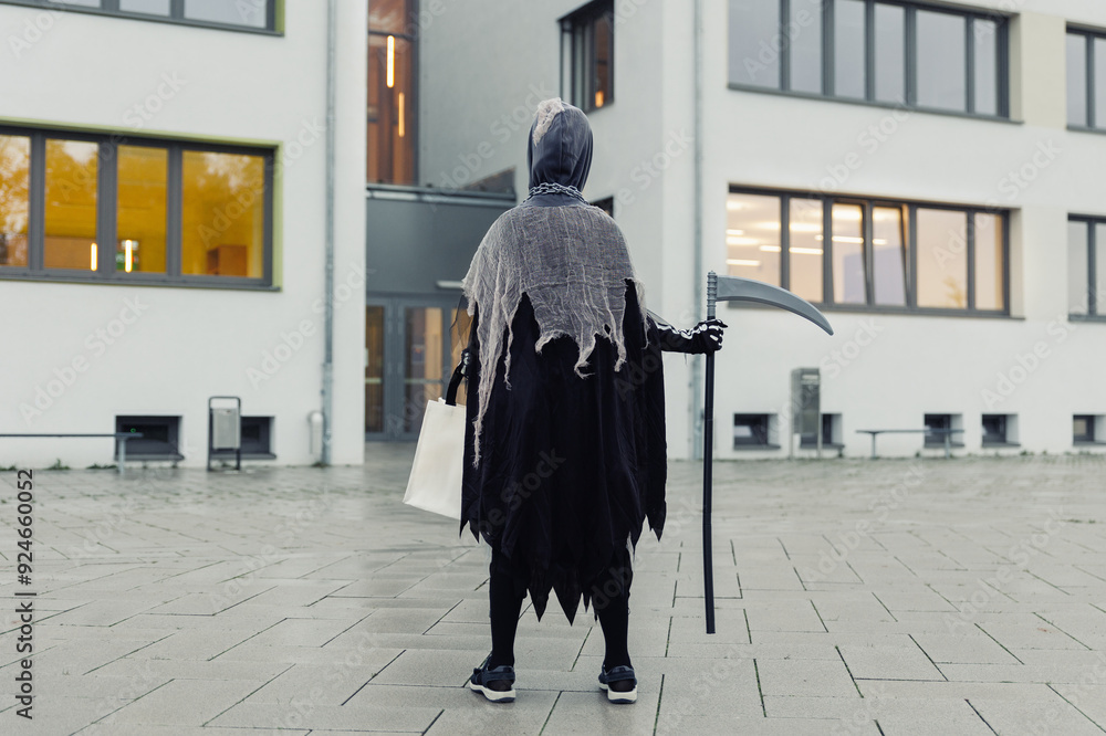 Back view of kid in grim reaper Halloween costume with scythe and bag ...