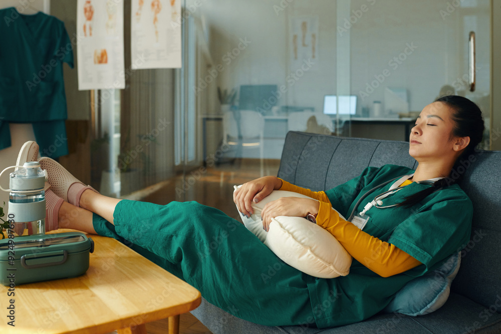 Female nurse in green scrubs taking well-deserved rest on couch in ...