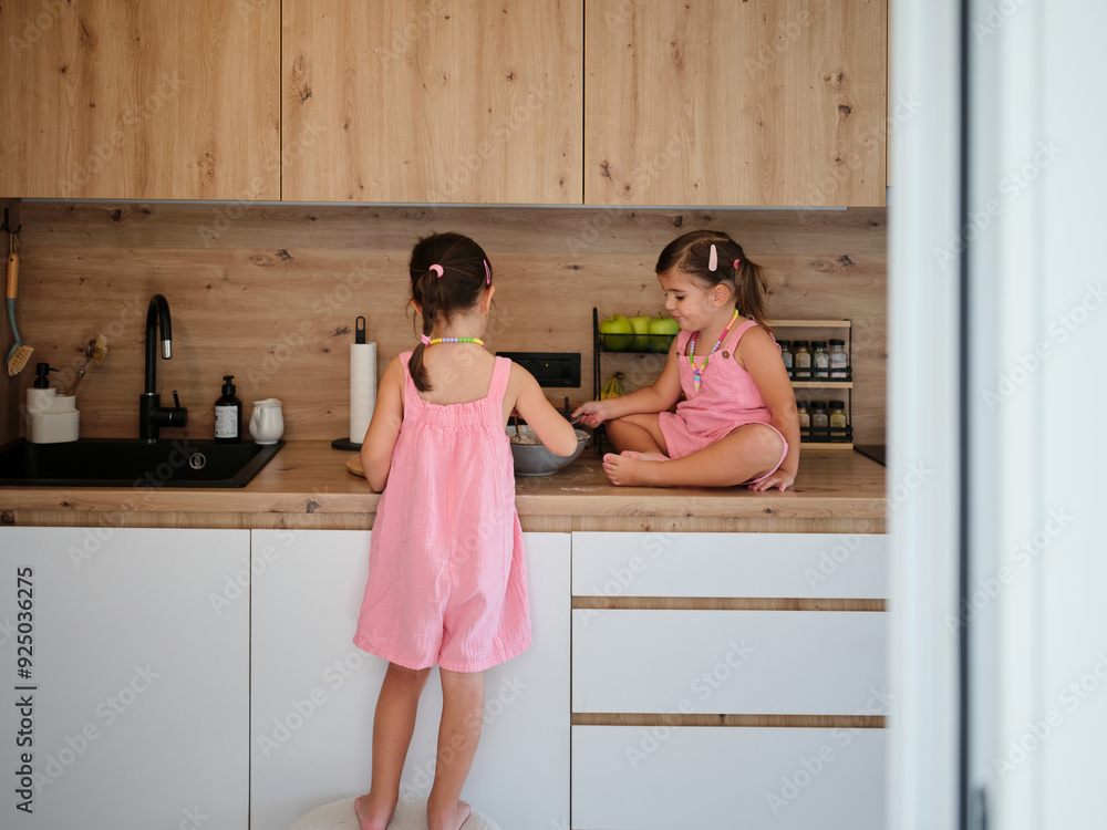 Two sisters are preparing dough together at the kitchen counter. They ...