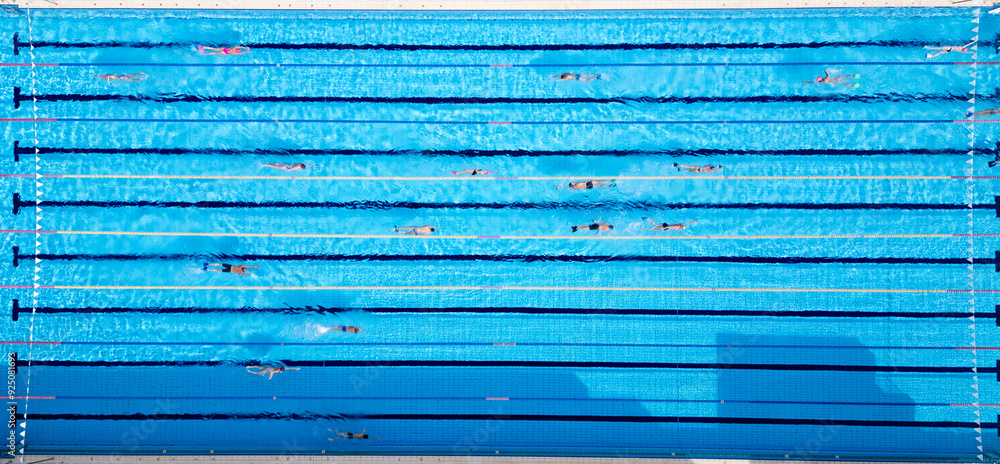 Drone video of swimmers in a clear blue pool, captured from above. The ...