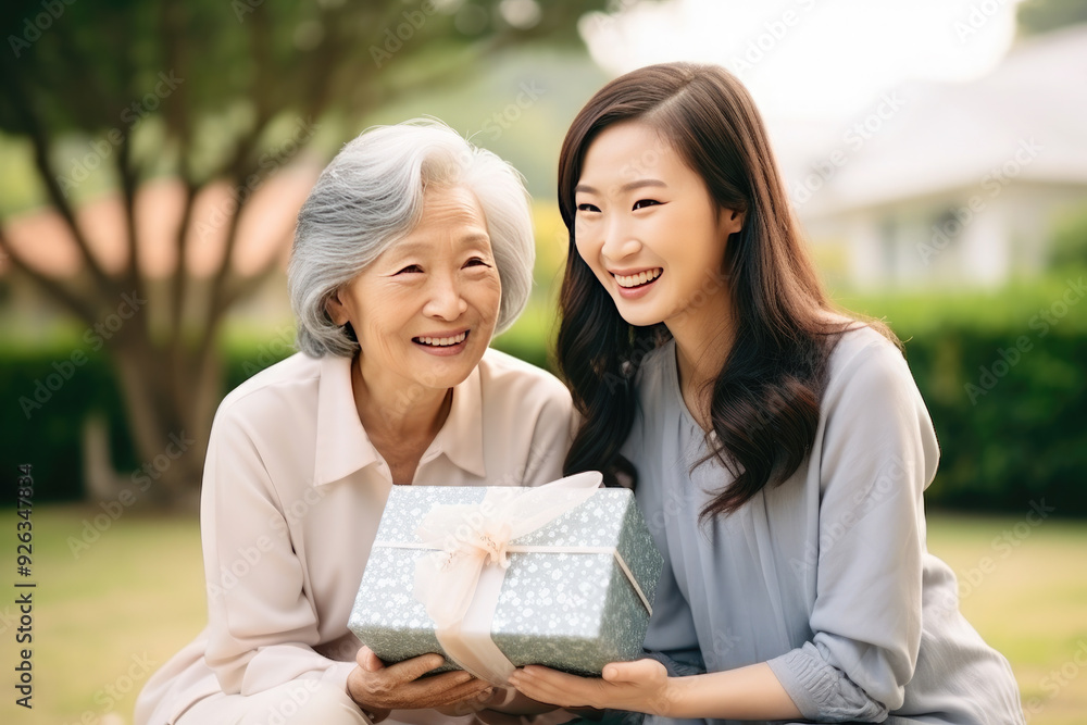 Granddaughter is giving a gift to her happy grandmother for keiro no hi, the japanese holiday ...