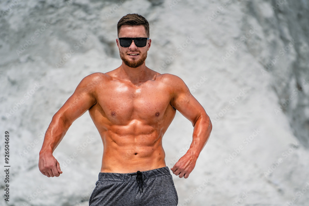 Fitness enthusiast posing confidently at the beach in sunny weather. A ...