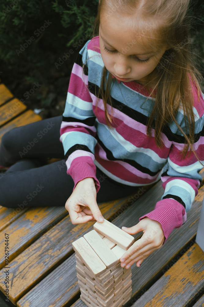 Person stacking wooden blocks, building tower while seated at a table ...