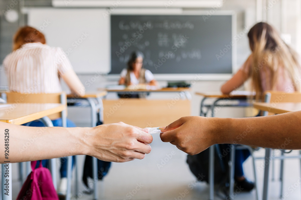 Young teenage boy giving cheat sheet to classmate during examination in ...