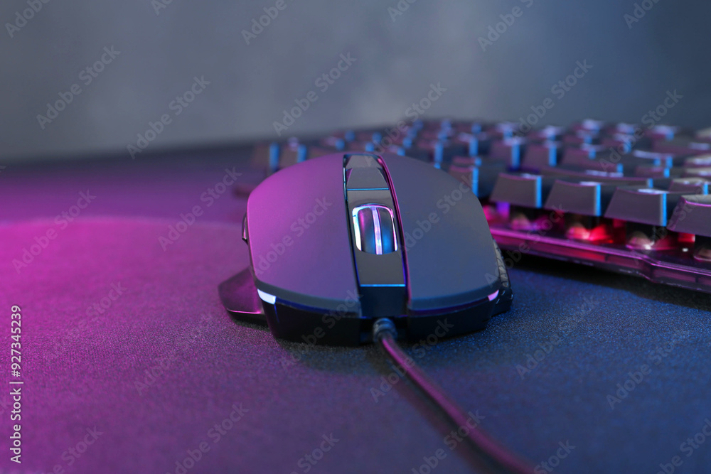 Computer mouse and RGB keyboard in neon lights on dark background ...