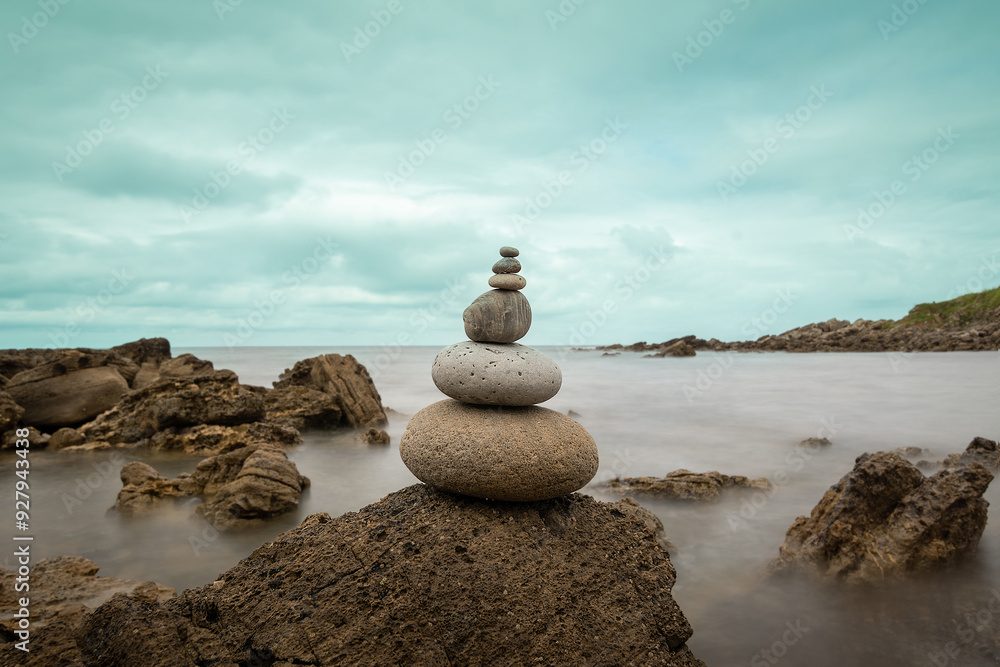 The image shows a stack of seven smooth stones balanced on a rocky ...