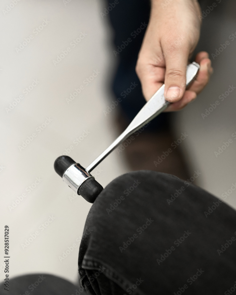 neurologist taps patient's knee with hammer and tests knee reflex ...