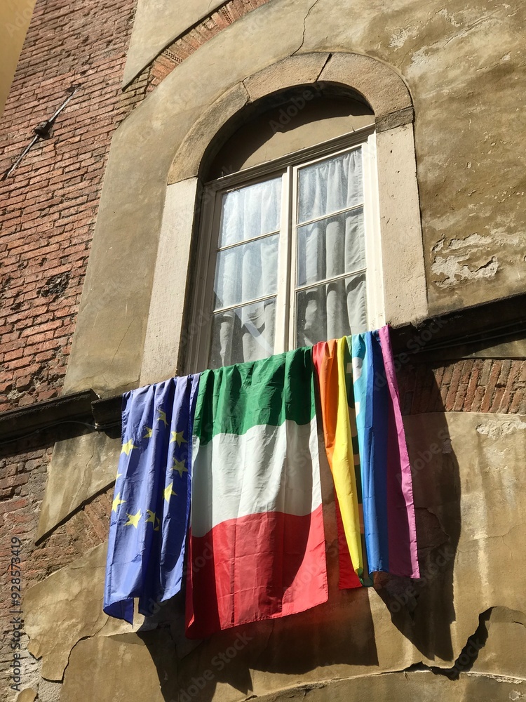 Flags on the window. Flags of the European Union, Italy and the rainbow ...