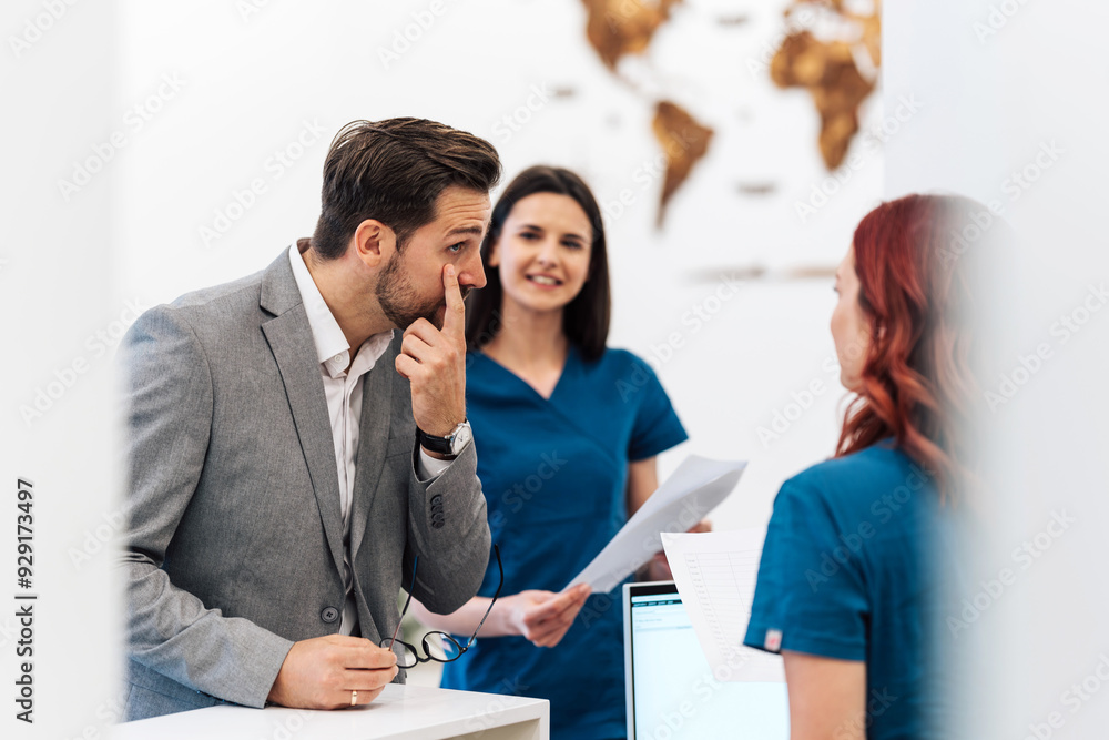 Handsome male patient standing at hospital reception counter and ...
