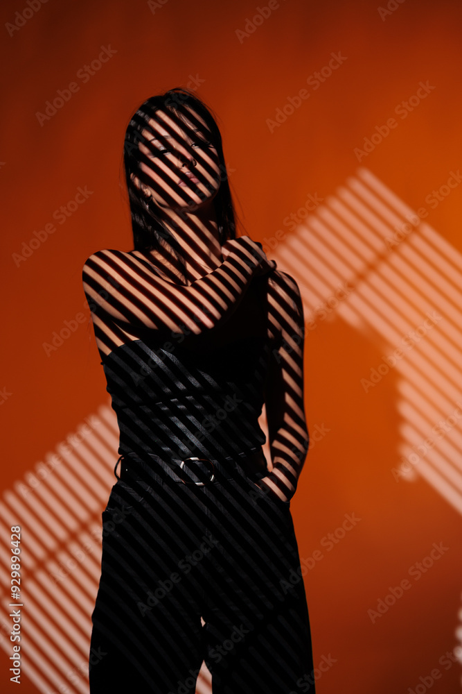 Brunette girl posing in a beam of light in the studio, on a red ...