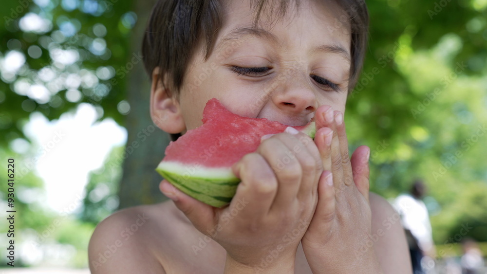 Boy enthusiastically biting into a slice of watermelon, close-up shot ...