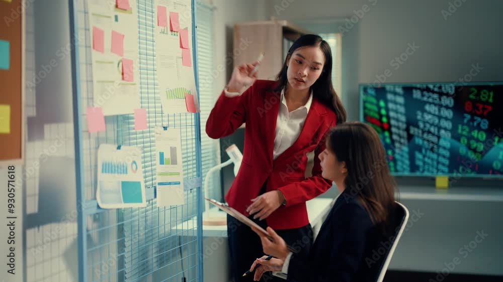 Two asian businesswomen, possibly financial analysts, are brainstorming ...