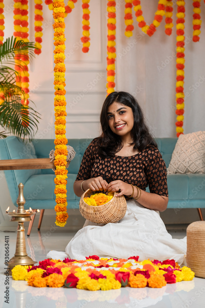 Young female model holding flower basket and making Onam pookalam ...