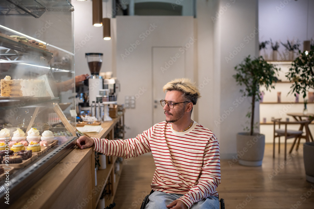 Focused disabled man in wheelchair looks at pastries, desserts in cafe ...