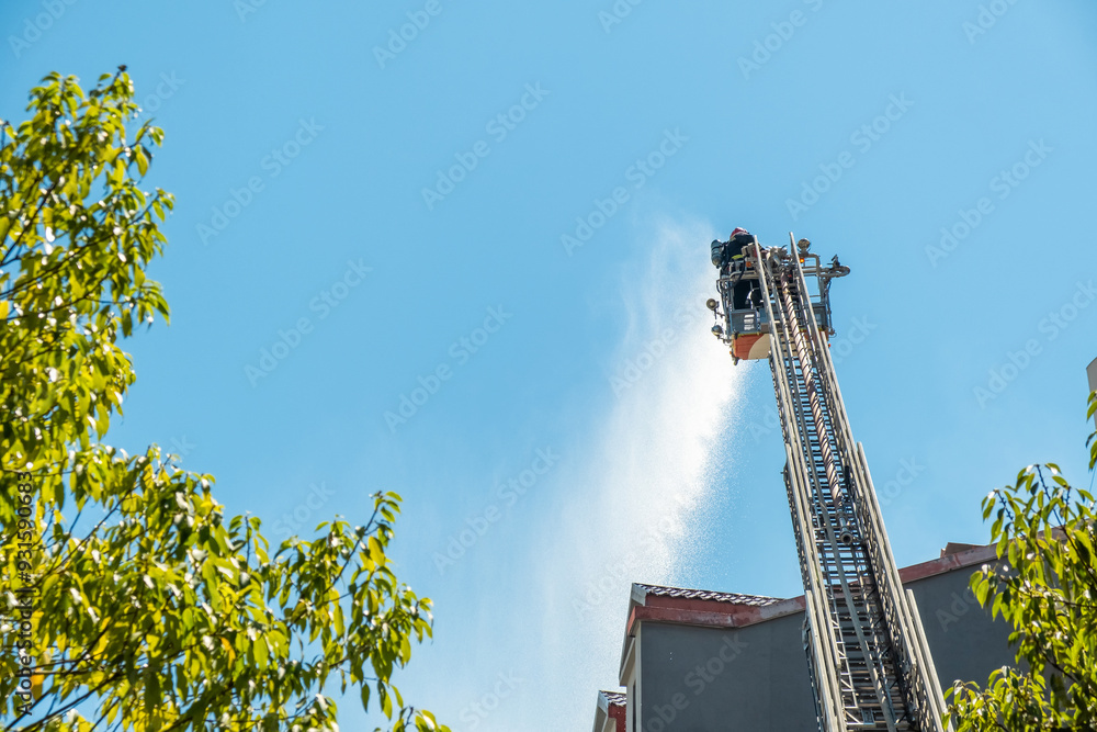 Rear view of firefighters extinguish fire on the roof of house using ...