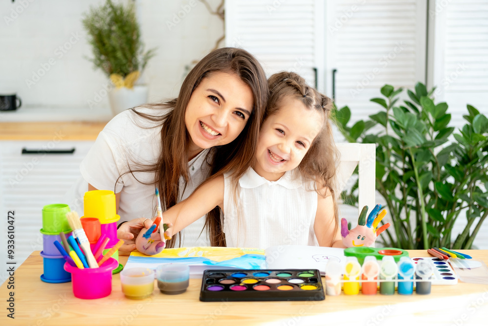 mom and a drawing teacher teaches a little girl child to draw with ...