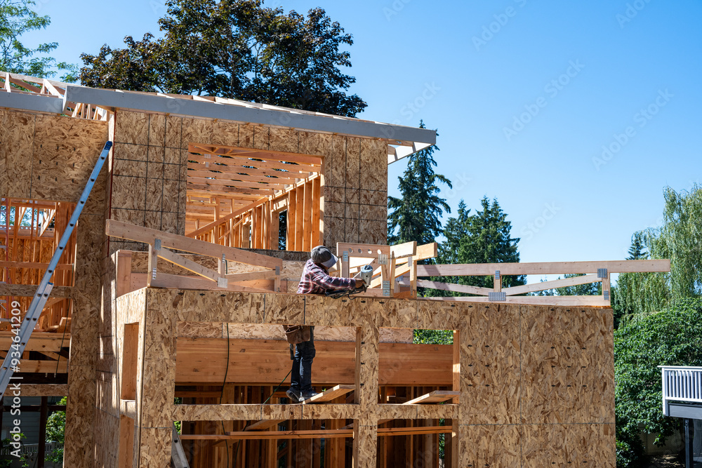 New residential home construction in framing stage, workman with ...