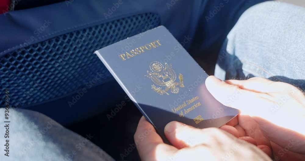 Hands holding an American passport while a passenger sits on an ...