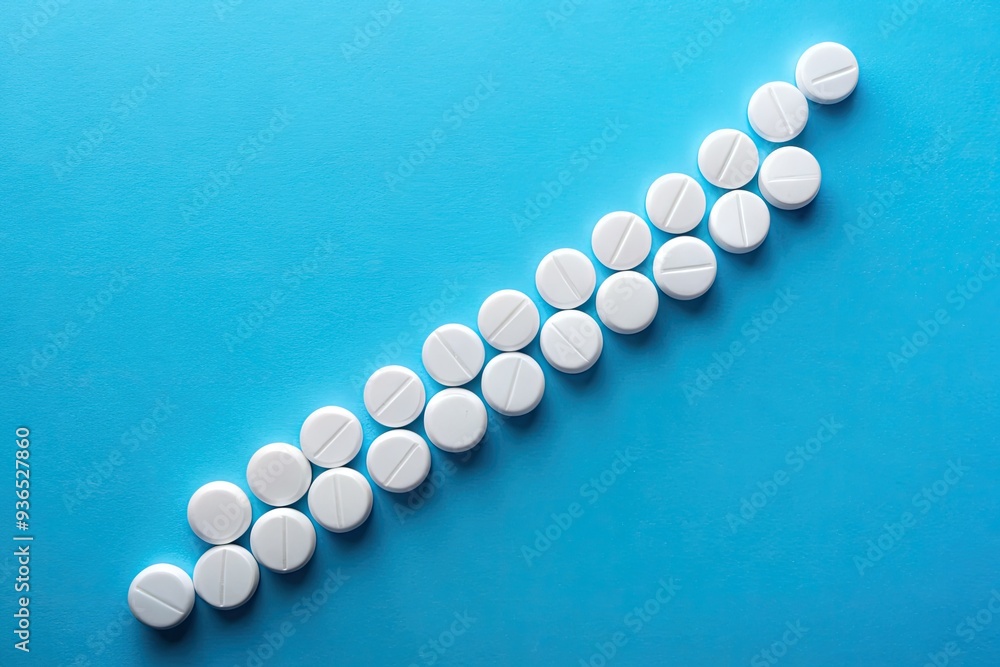 Gradient of white tablet pills forming a staircase on a bright blue ...