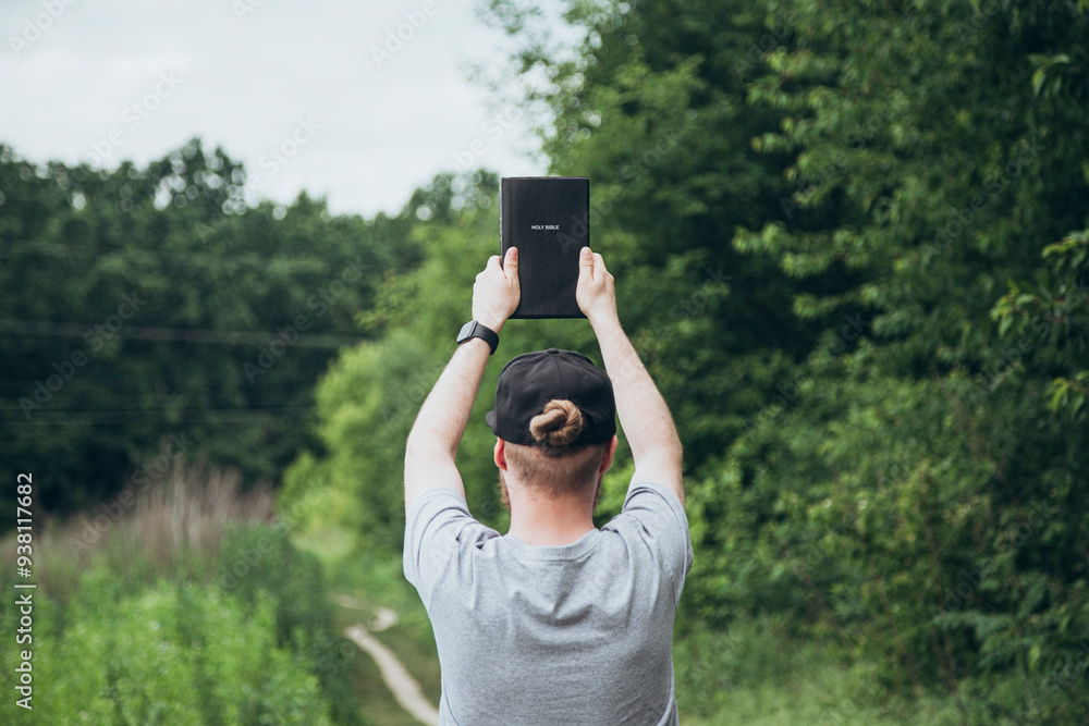 Christian man holds holy bible in hands raised on nature background ...
