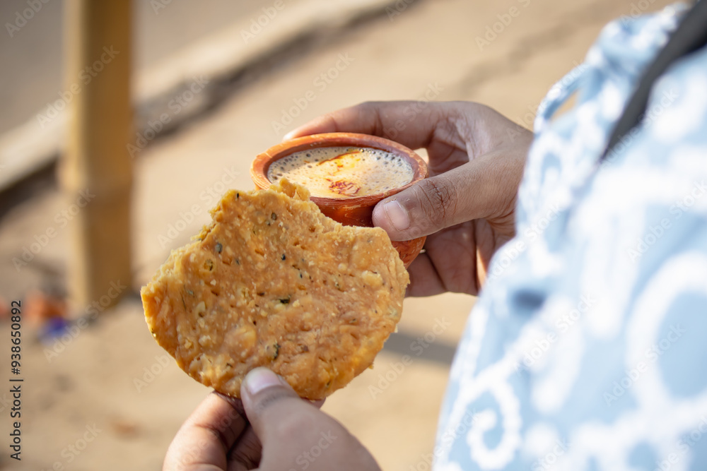 Mathri with hot tea in clay pot held in hand for eating in morning as ...