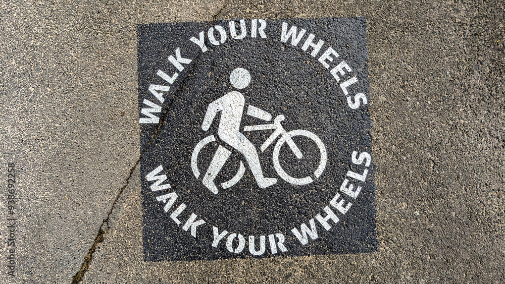 No cycling sign painted on footpath saying walk your wheels with symbol ...