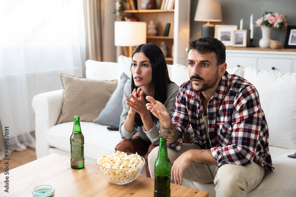 Serious Couple Watches TV together while Sitting on a Couch in the ...