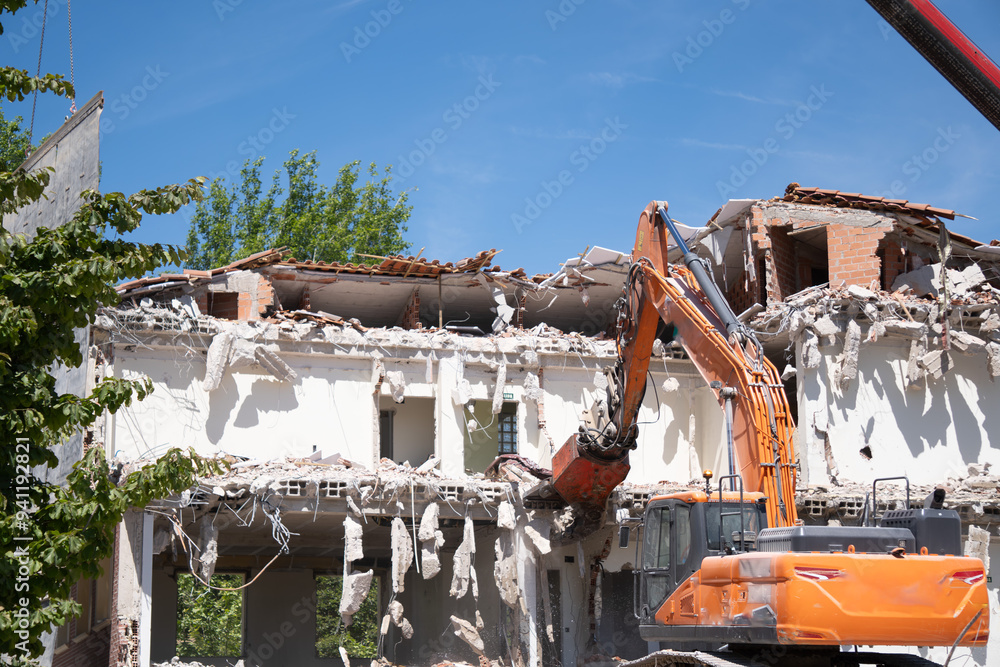 chaotic demolition of a building with a large orange bulldozer with a ...