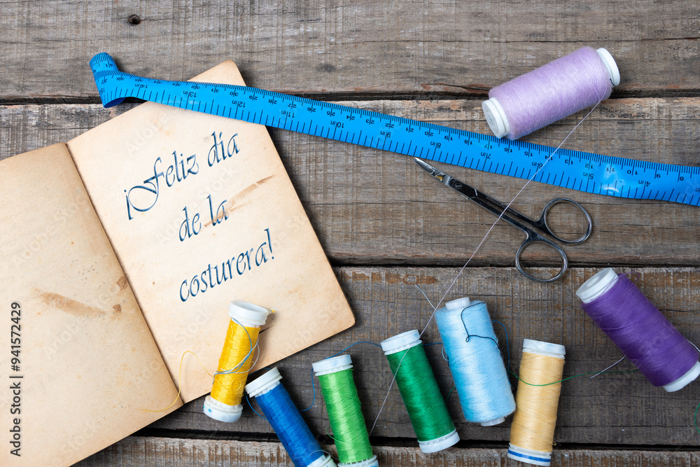 Spool of thread, measuring tape, scissors and message in Spanish Feliz ...