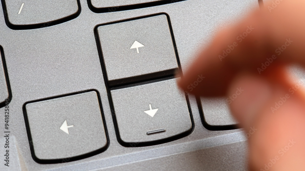 Man pressing the up arrow key on a modern laptop computer keyboard ...