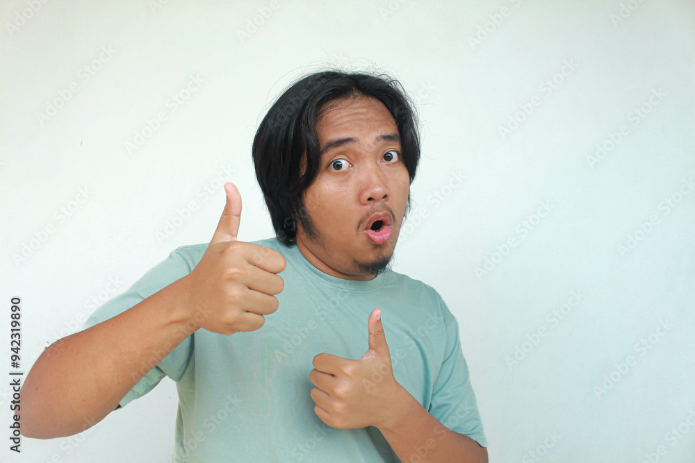 Excited and happy long haired Asian man gives thumbs up hand gesture of ...