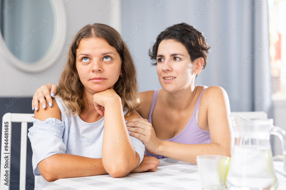Two lesbian women. Frustration woman sitting at home and her partner ...