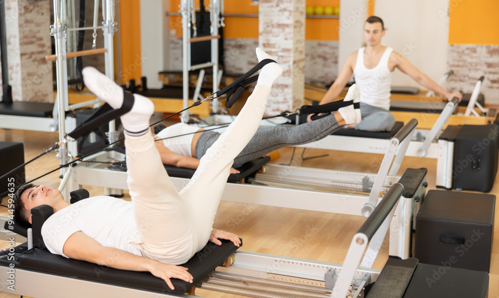 Motivated young guy performing focused rehabilitation feet-in-strap ...