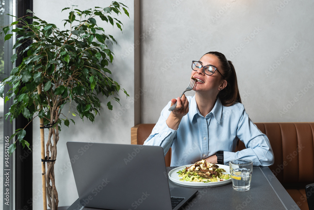 Young business woman working remotely from cafeteria during lunch break ...