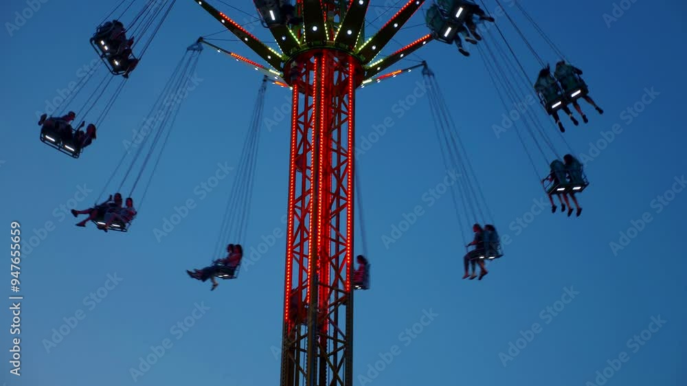 A vibrant amusement ride adorned with glowing lights against the night ...