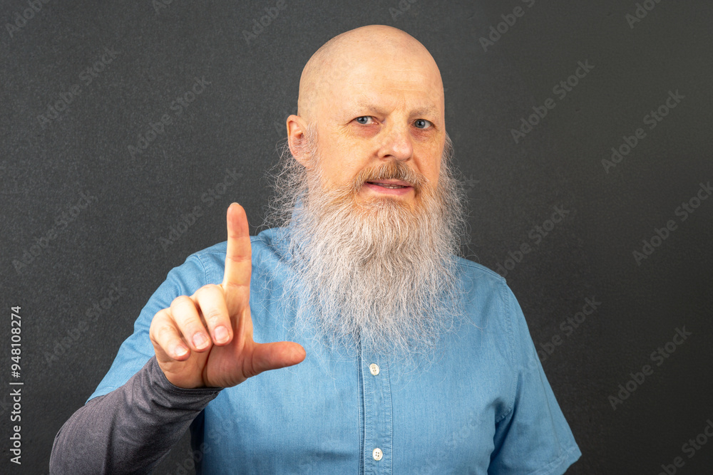 bald man with a long gray beard wearing a blue shirt, making a gesture ...