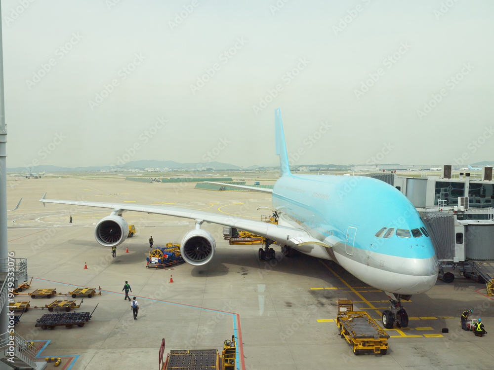 Blue Wide-body twin-deck airliner on the ground with jet bridge ...