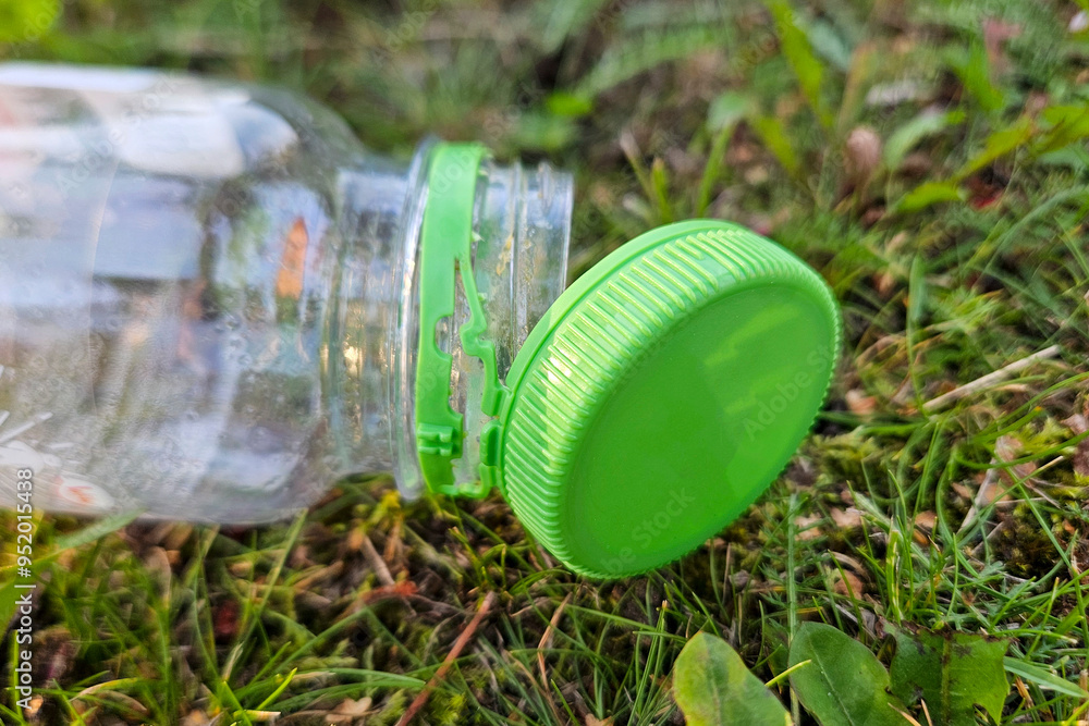 A discarded bottle with a tethered cap on the grass. EU regulation ...