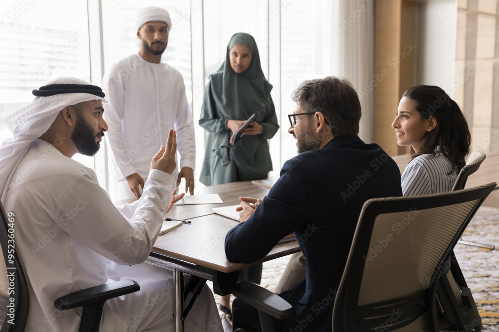 Diverse business team talking at meeting table. Arabian and European ...