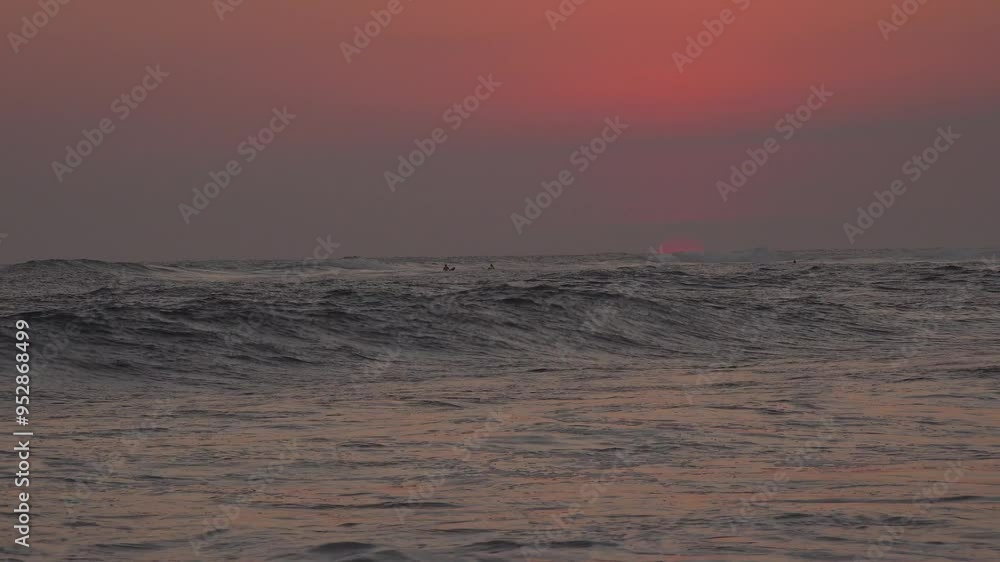 Surfers on the ocean as the red sun sinks behind them Stock Video ...