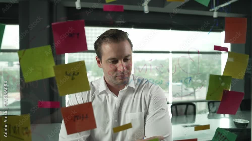 Professional male leader writing marketing idea on sticky notes ...