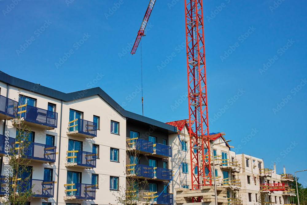 Red construction crane is building modern apartments in residential ...